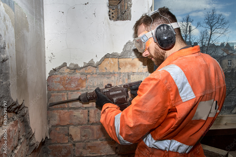 Construction worker using hammer drill with chisel for demolition jobs ...