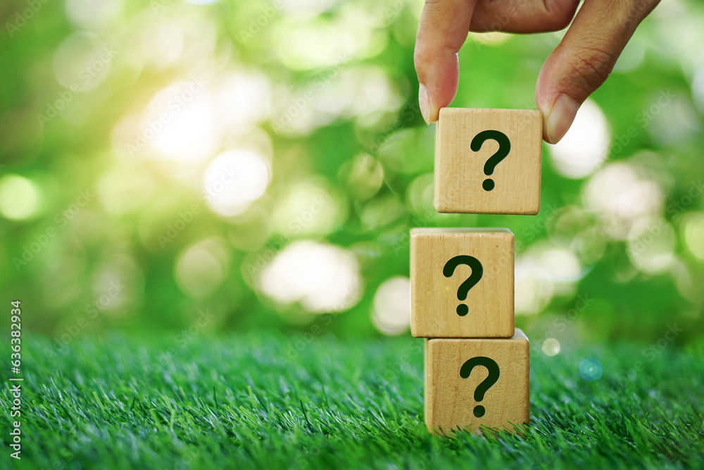 Hand placed a wooden block with question mark sign on stacking of them ...