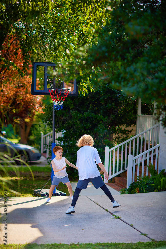 happy kids playing basketball at the driveway of their home. portable ...
