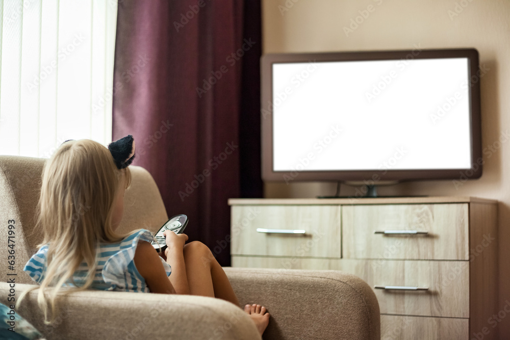 Rear view of little girl kid 5-6 year old watching tv sits on armchair ...