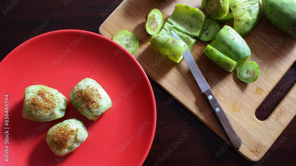 Plato rojo con tres tunas verdes con chile en polvo encima y tabla de ...