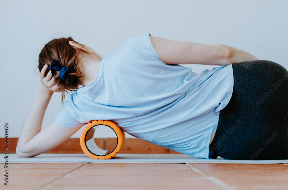Woman rolling lower armpit on massage foam roller to release tension in ...