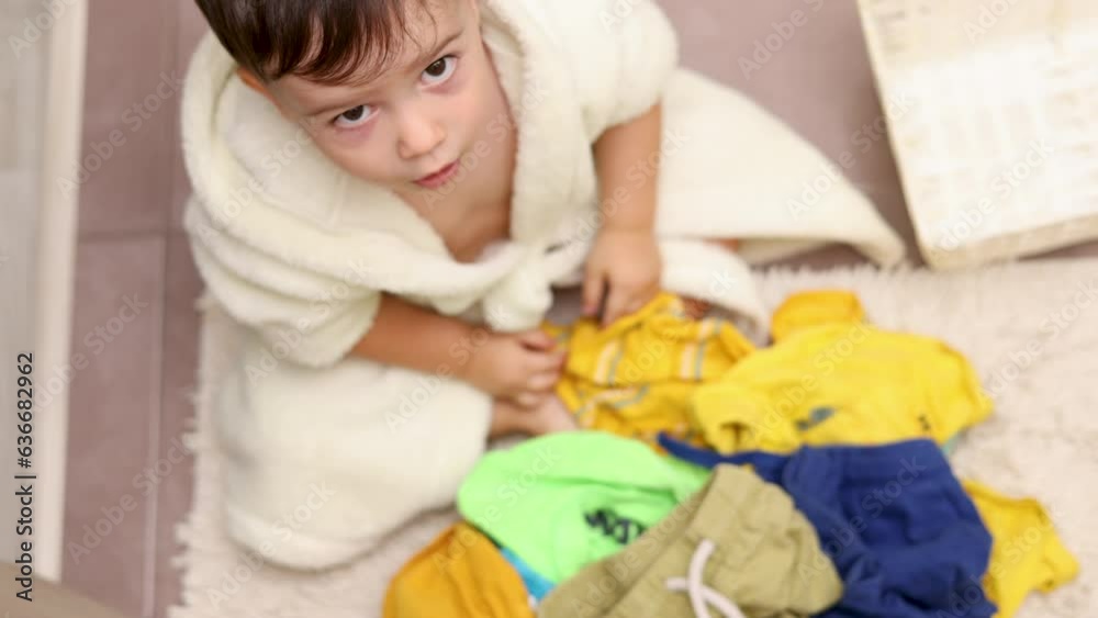 adorable cute baby boy in bathrobe putting or remove clothes from ...