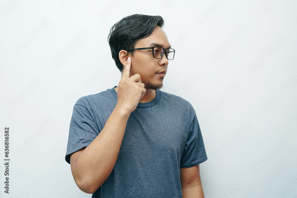 Portrait of Indonesian Asian man point his index finger on ear showing ...