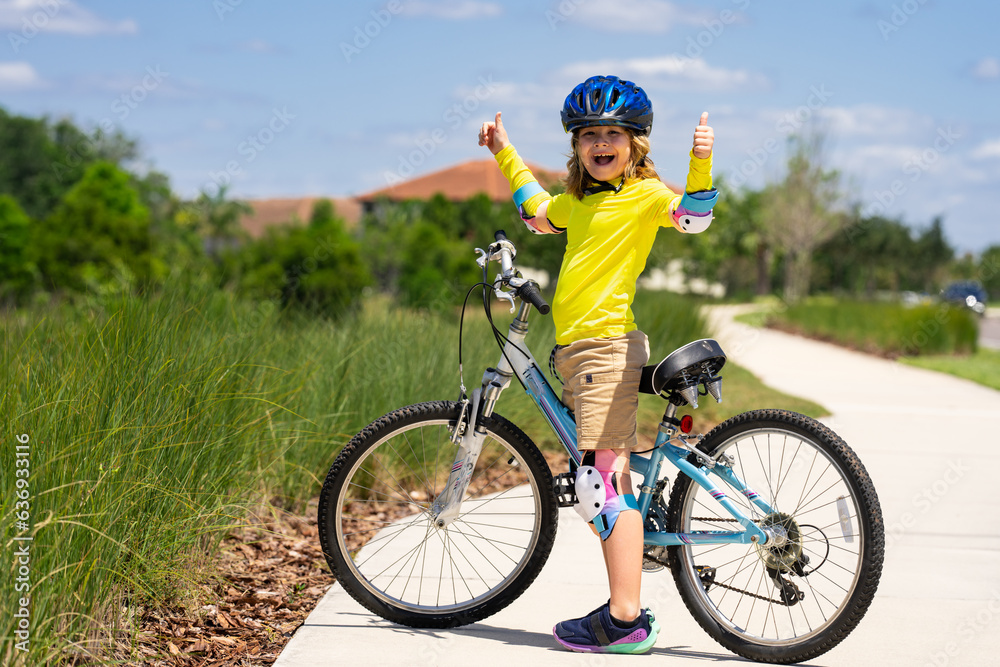Little kid boy ride a bike in the park. Kid cycling on bicycle. Happy smiling child in helmet ...