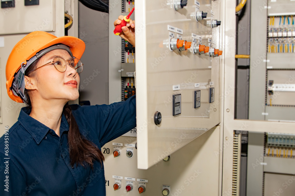Beautiful asian female electrician in safety helmet working on ...