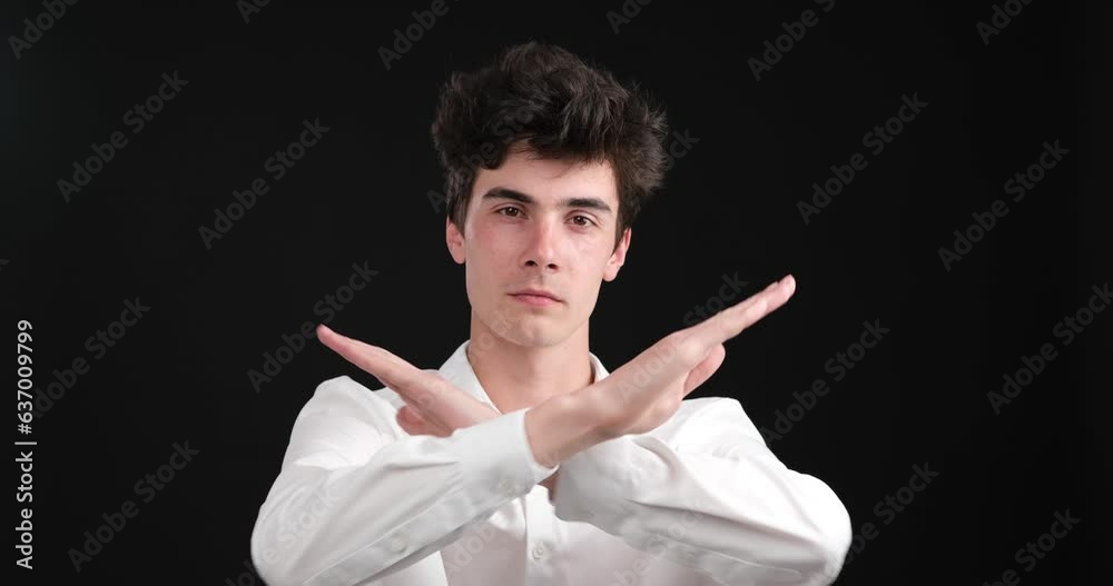 A handsome man stands confidently on a black background with his arms ...