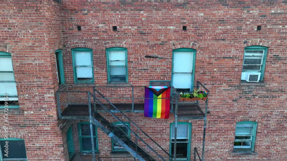Gay pride and transgender ally flag on fire escape of old brick inner ...