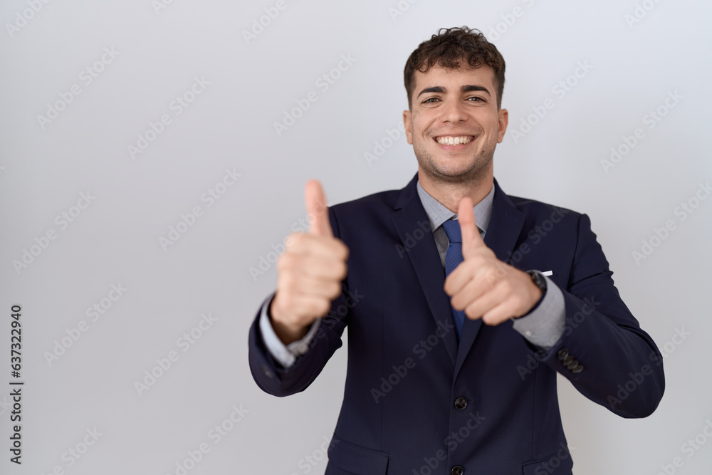Young hispanic business man wearing suit and tie approving doing ...