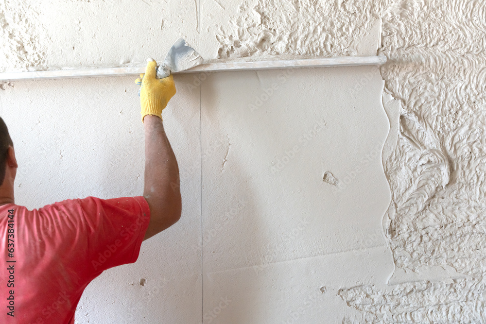 Plasterer levels the walls with gypsum plaster using an aluminum ...