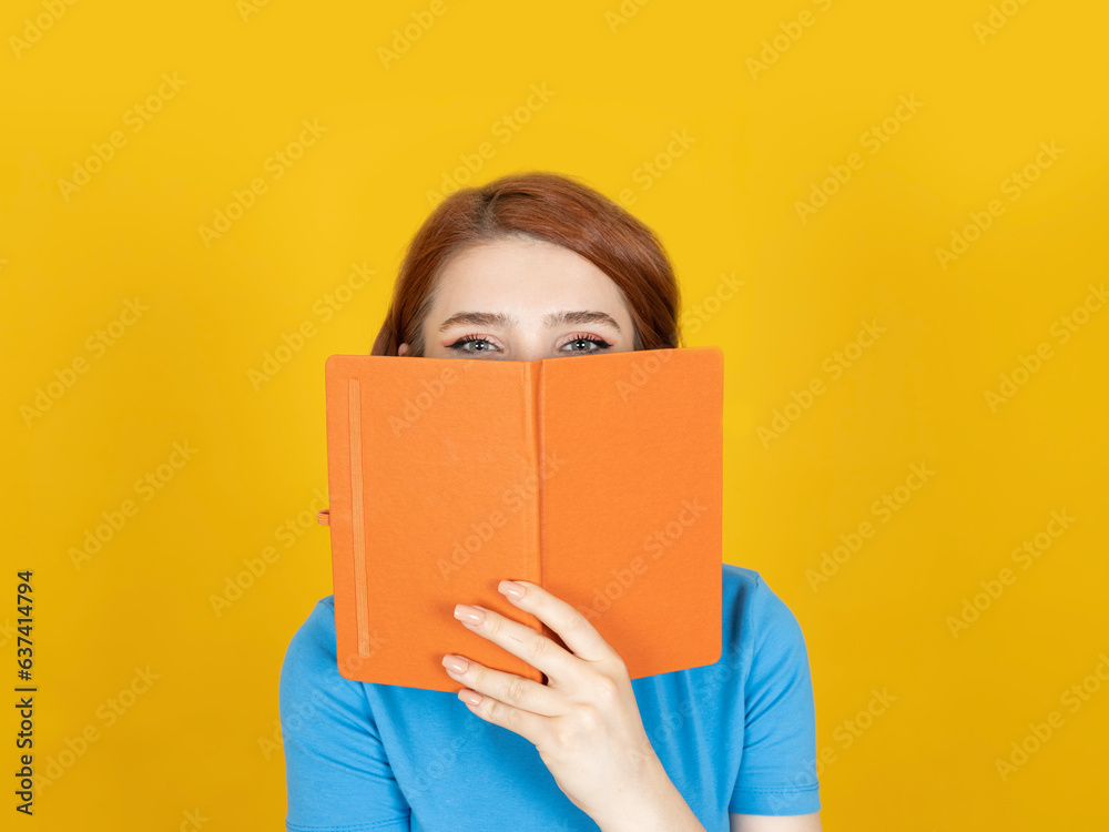 Hide her face behind a book, close up portrait of young European red ...