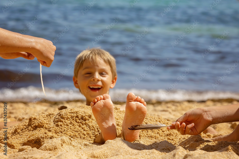Child, tickling sibling on the beach on the feet with feather, kid ...