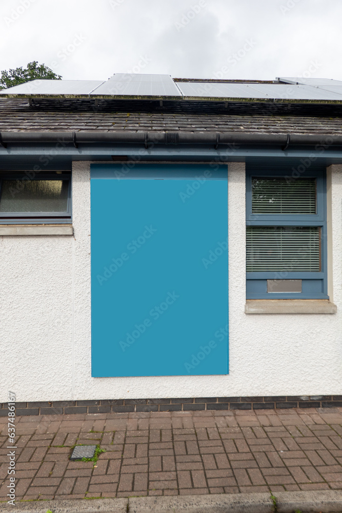 Blank blue rectangular sign on the side of a white building by a brick ...