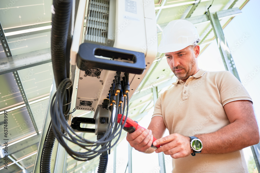 Bottom view of worker checking solar inverter work. Measuring output ...