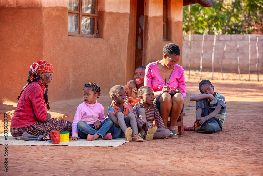 village african family sited in the yard in front of the house, three generations grandmother ...