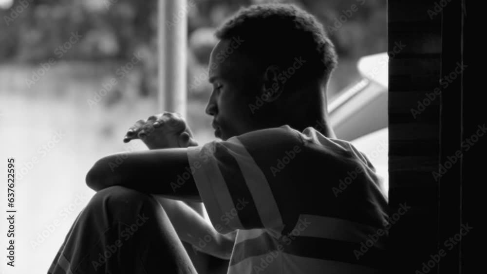 One young black man in despair in dramatic monochromatic, black and ...