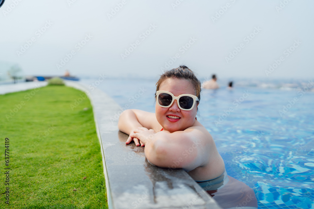 Overweight young asian woman wearing swimsuit relaxing in the pool ...