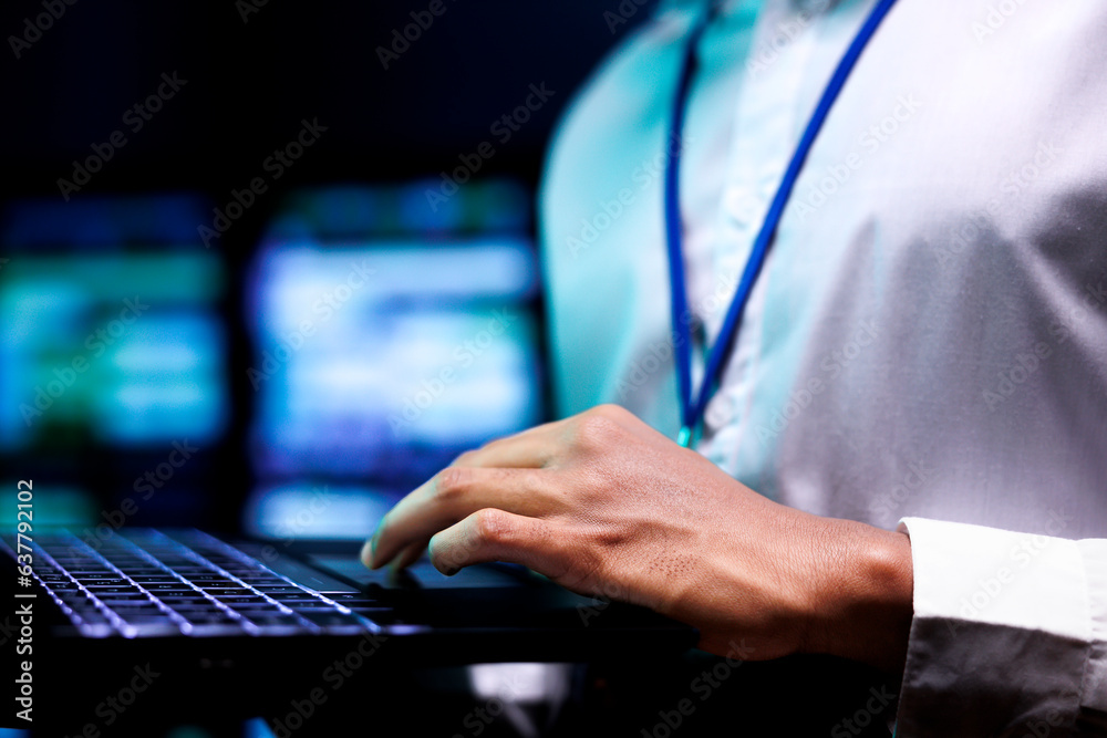 Computer scientist using laptop to analyze server cabinets providing ...