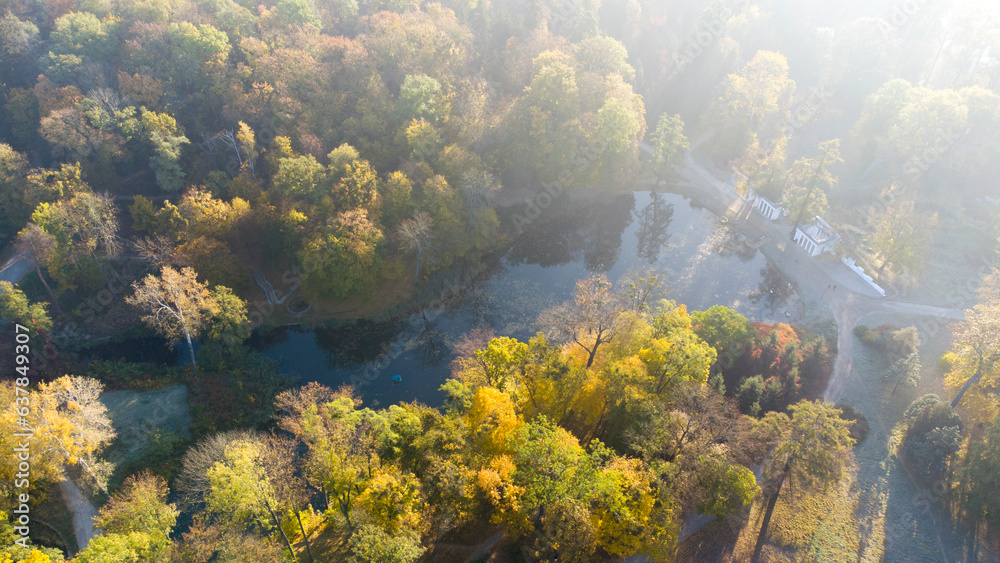 Aerial flying over trees with yellow leaves, lake, columns and walking ...