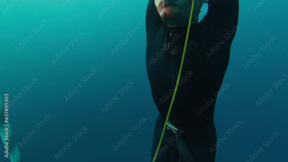 Freediving on the rope in a sea. Male freediver descends along the rope ...