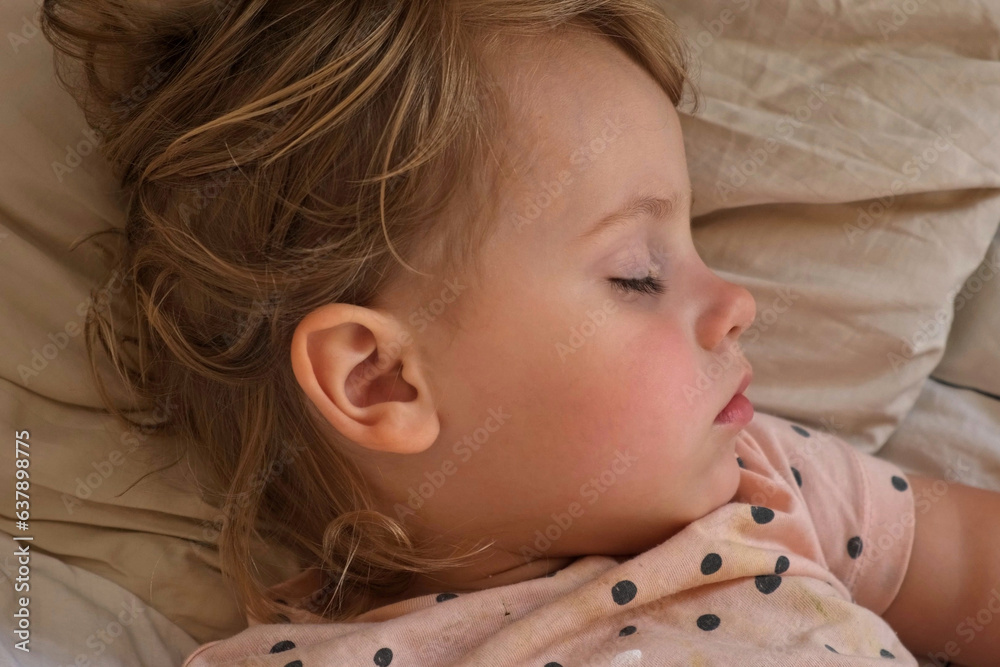 Peaceful adorable baby sleeping on a bed at home. Slumbering little child. Two year old girl ...