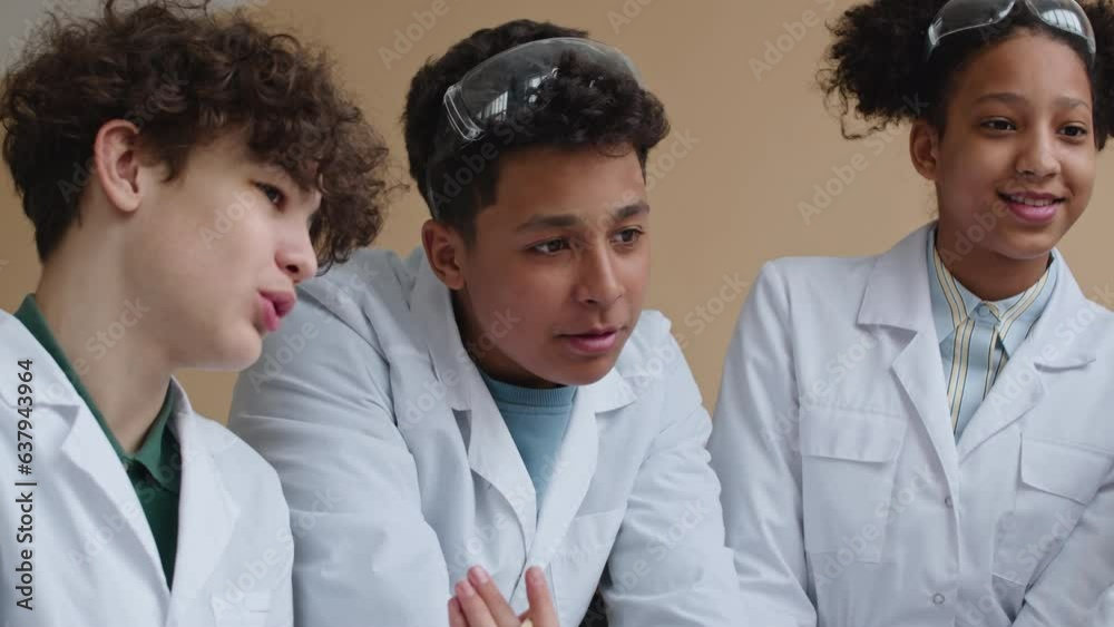 Waist up of diverse preteen schoolkids wearing white lab coats chatting ... Waist up of diverse preteen schoolkids wearing white lab coats chatting ...