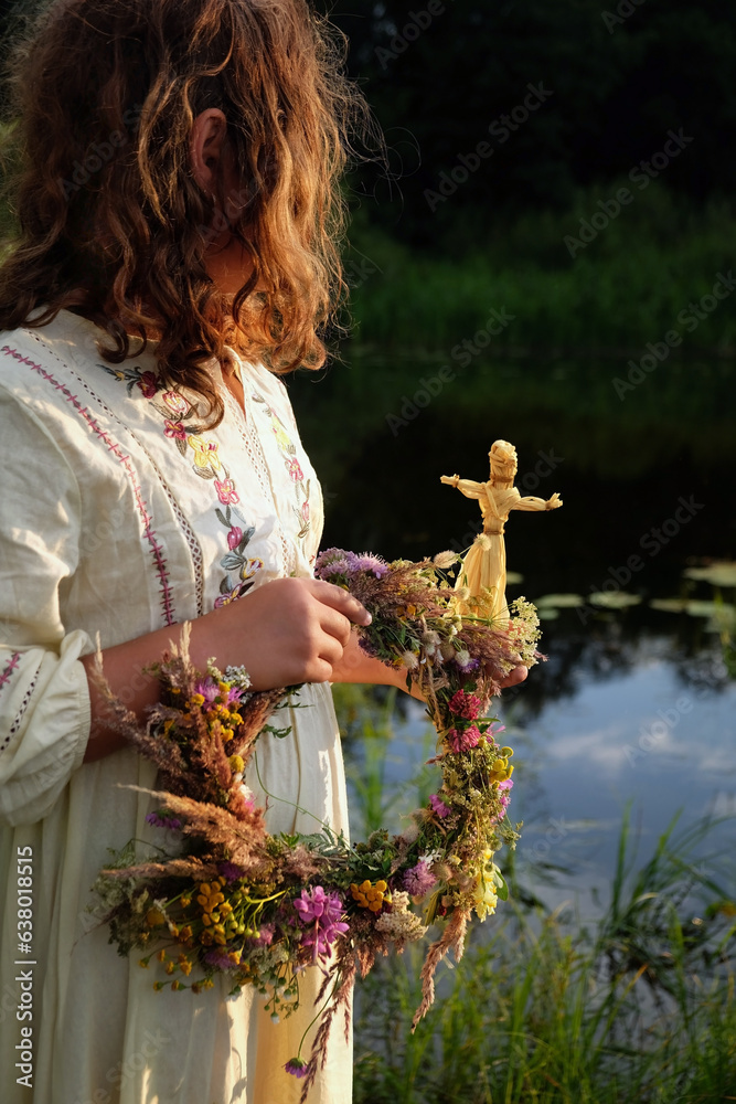 Girl with floral wreath and corn doll in hands outdoor, natural ...