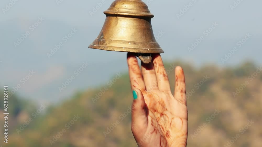 Closeup shot of hand of an Indian man ringing the bell of the temple. Devotee ringing the temple ...