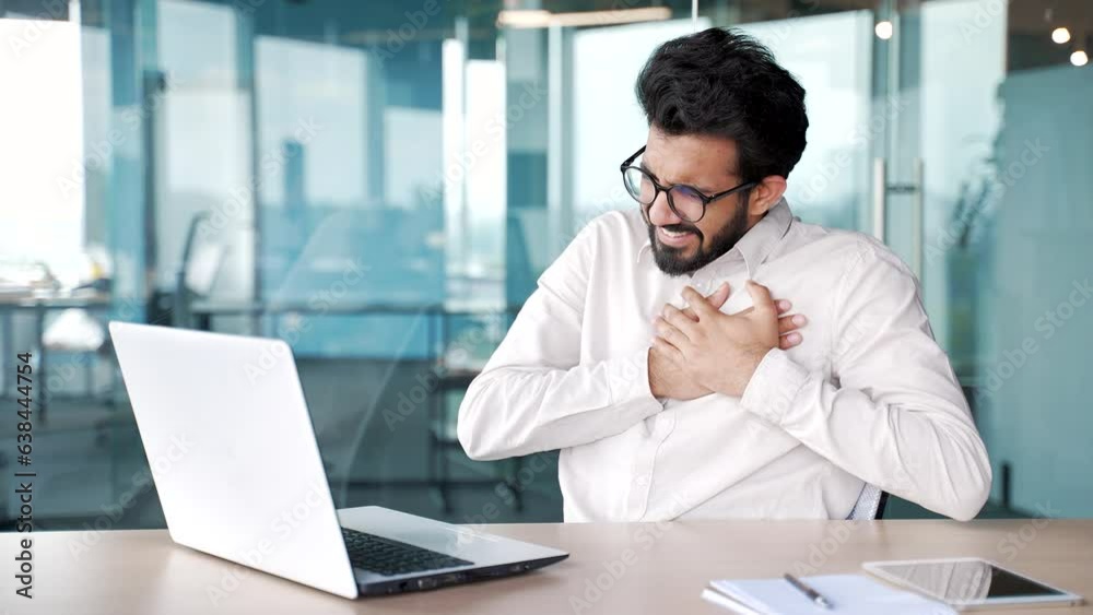 A young businessman has a heart attack while working on a laptop while ...