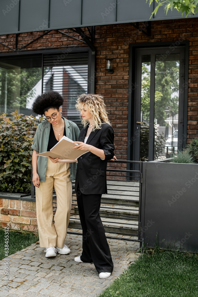 blonde real estate agent showing documents to african american client ...
