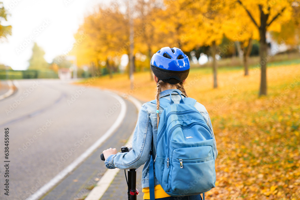 Road to school. Kid riding scooter on autumn city street. Child girl ...