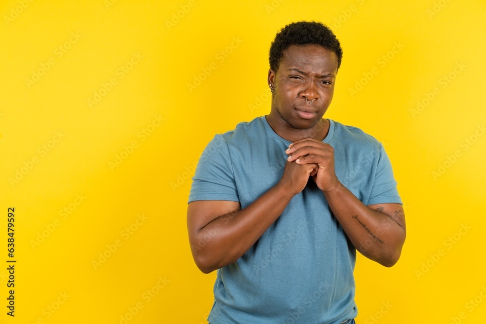 Sad handsome African American standing over yellow studio background ...