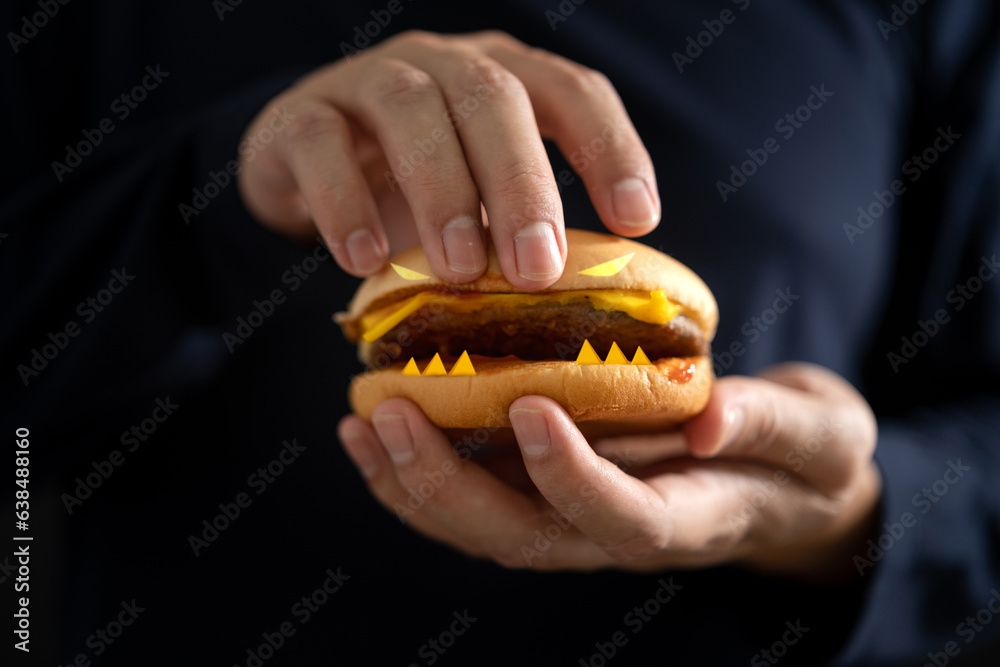 Man's hand holding a hamburger with monster teeth, concept of horror ...