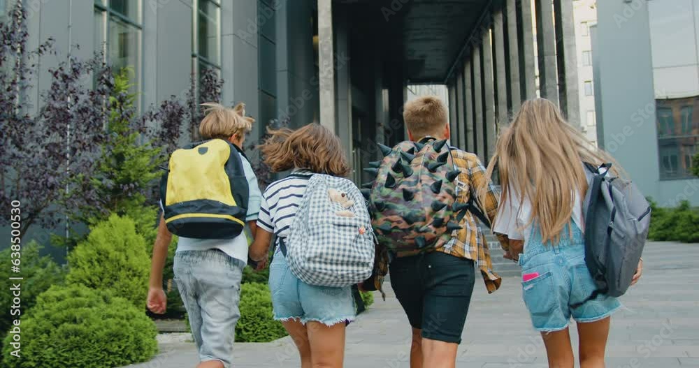 Rear view. Good-looking school child friends climb stairs going to ...