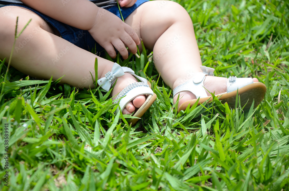 A girl with her pale-skinned legs, sitting on the green grass of the ...