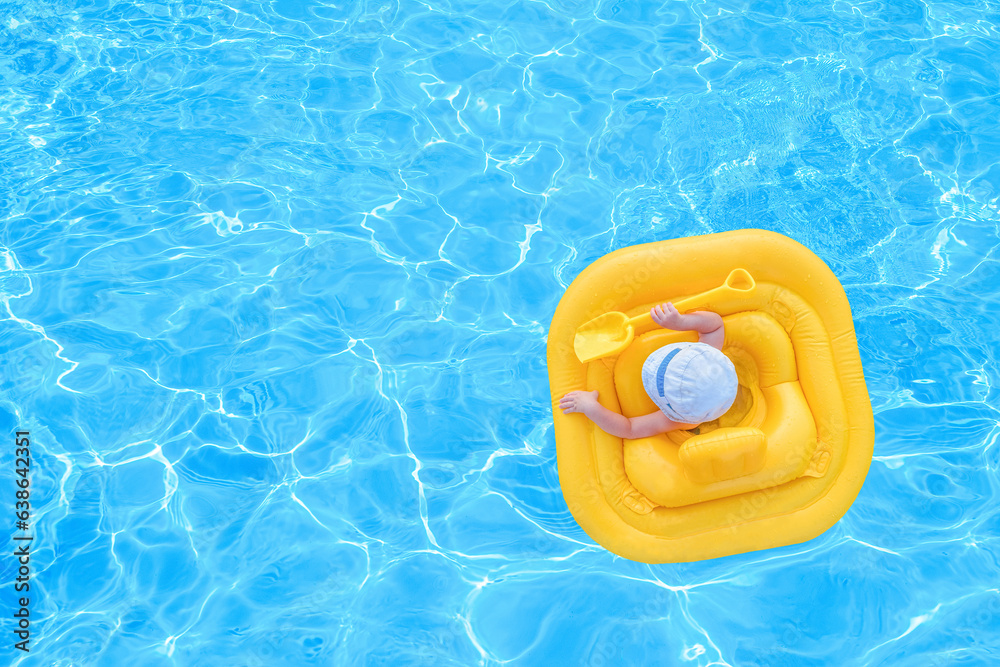 Baby swim in a yellow inflatable raft in a pool of blue water. Small ...