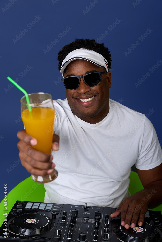 Black man DJ on a blue background plays music, relaxes and drinks a ...
