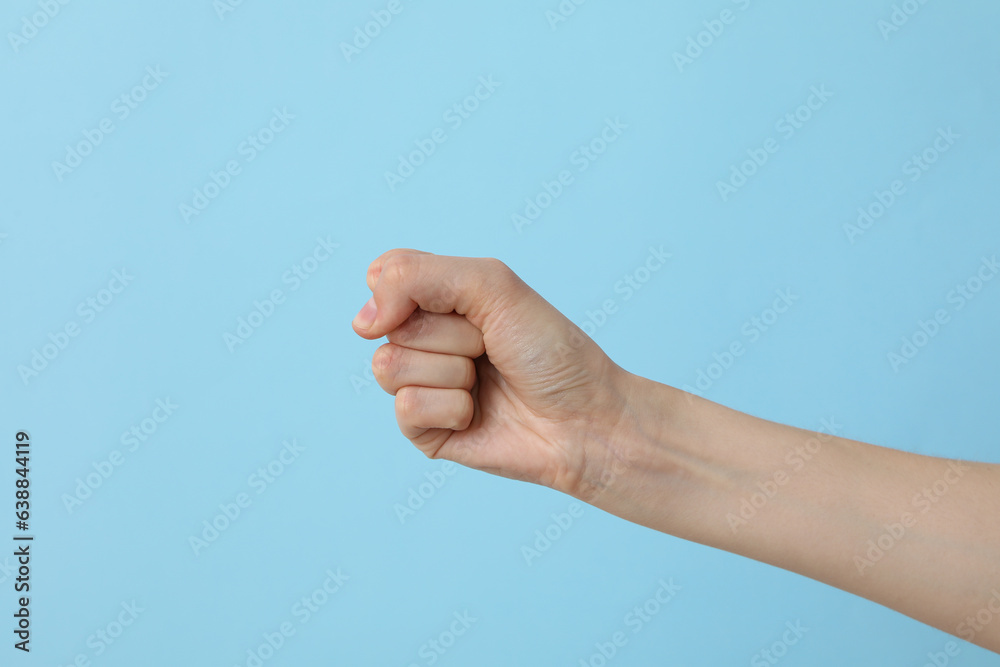 Female hand clenched into a fist on a light blue background Stock Photo ...