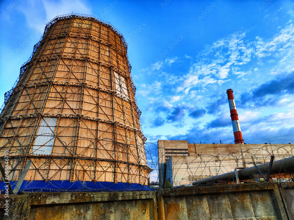 CHP cooling towers from which smoke is coming out against blue sky. A ...