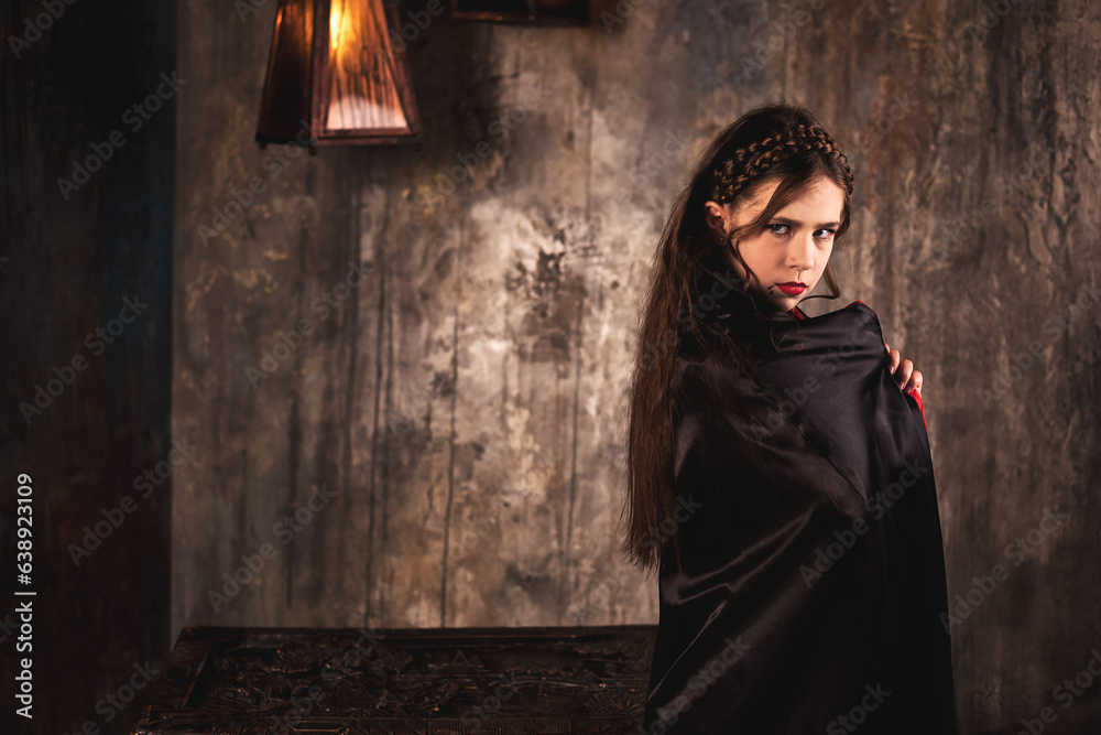 Frowning vampire in cloak posing near chest in underground castle dark ...