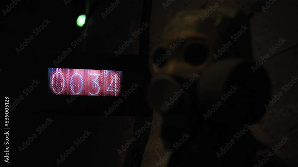 Close-up of a stopwatch with red numbers and a gas mask in a dark ...