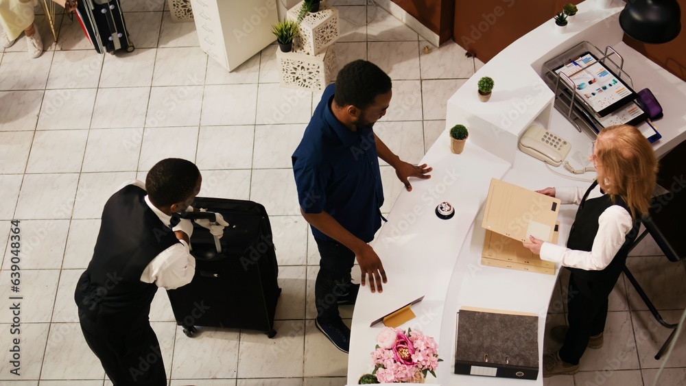 Male tourist arriving at hotel reception, preparing to do check in and ...
