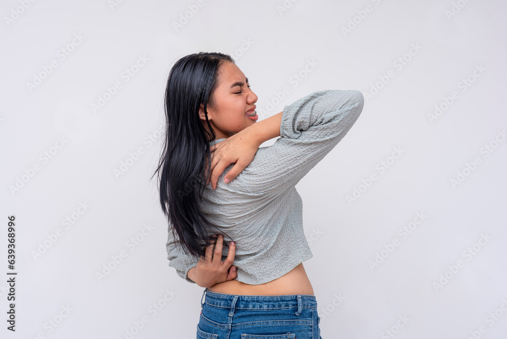 A young asian woman struggles to reach her back. A futile attempt to ...