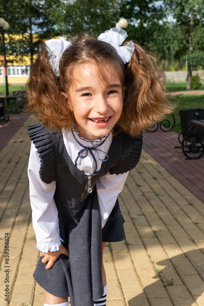 Cheerful funny girl with a toothless smile in a school uniform with ...