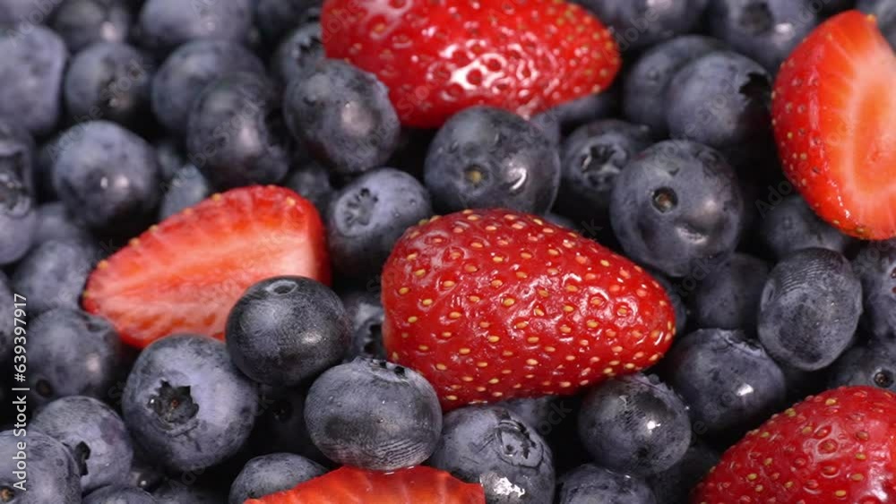 Blueberries and strawberries rotate on their axis on turntable. Forest ...