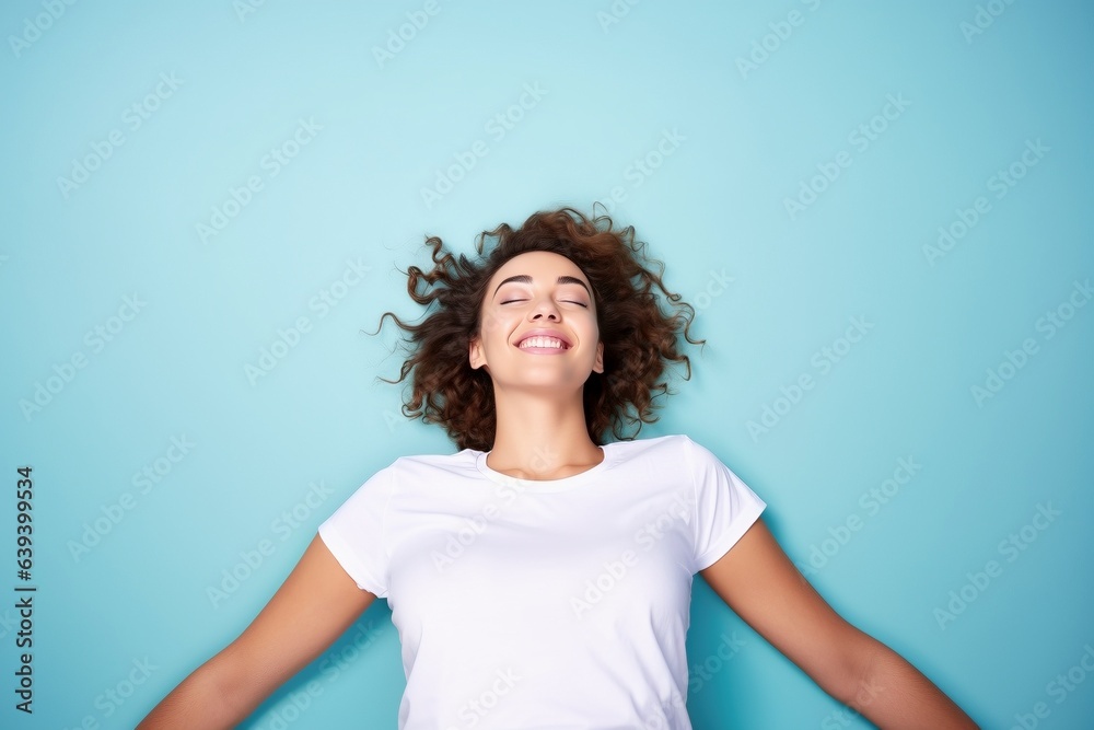female laying down on back wearing white tshirt on blue background for ...