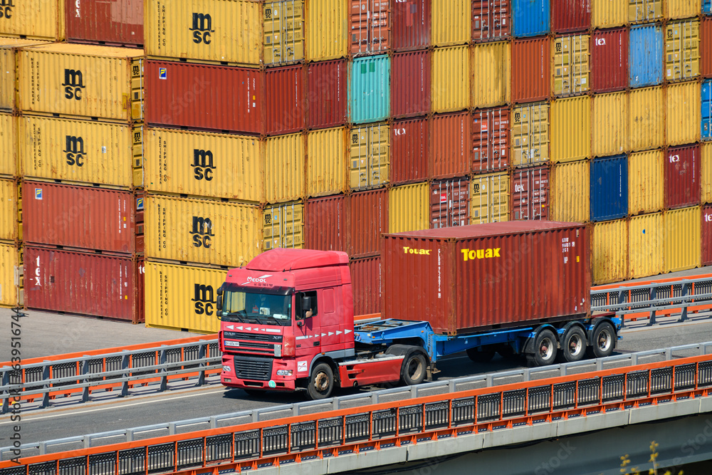 truck transports container through industrial seaport, warehouses with ...