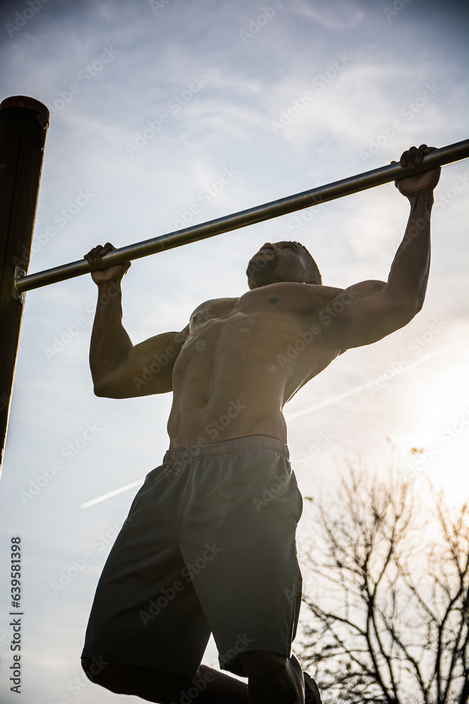 man showcasing his strength and working out by pulling up a bar in a ...