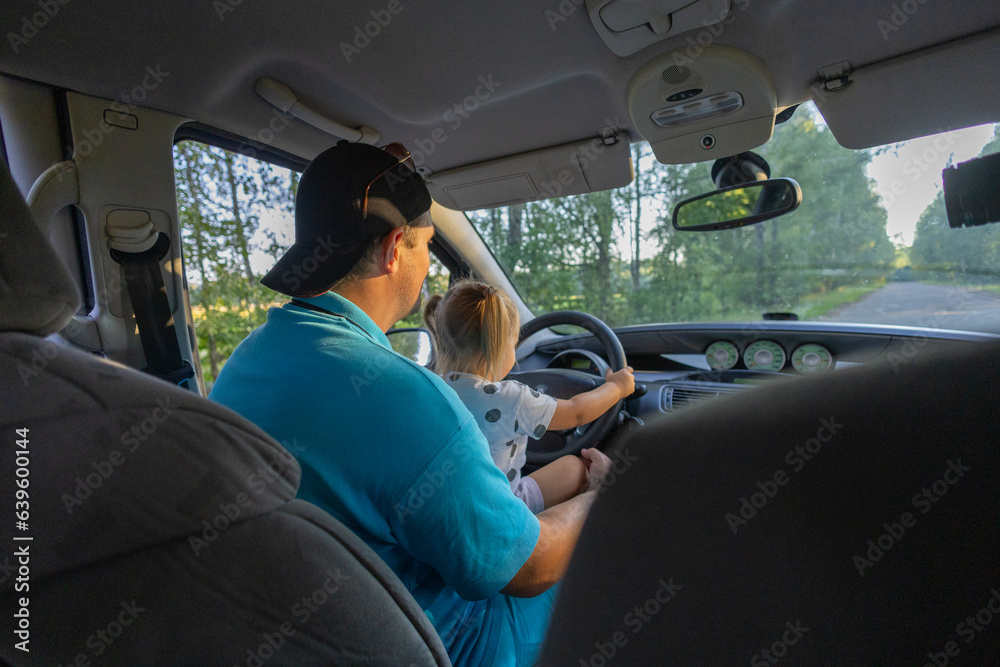 Fotka „The father put the little daughter on his lap and let him drive ...