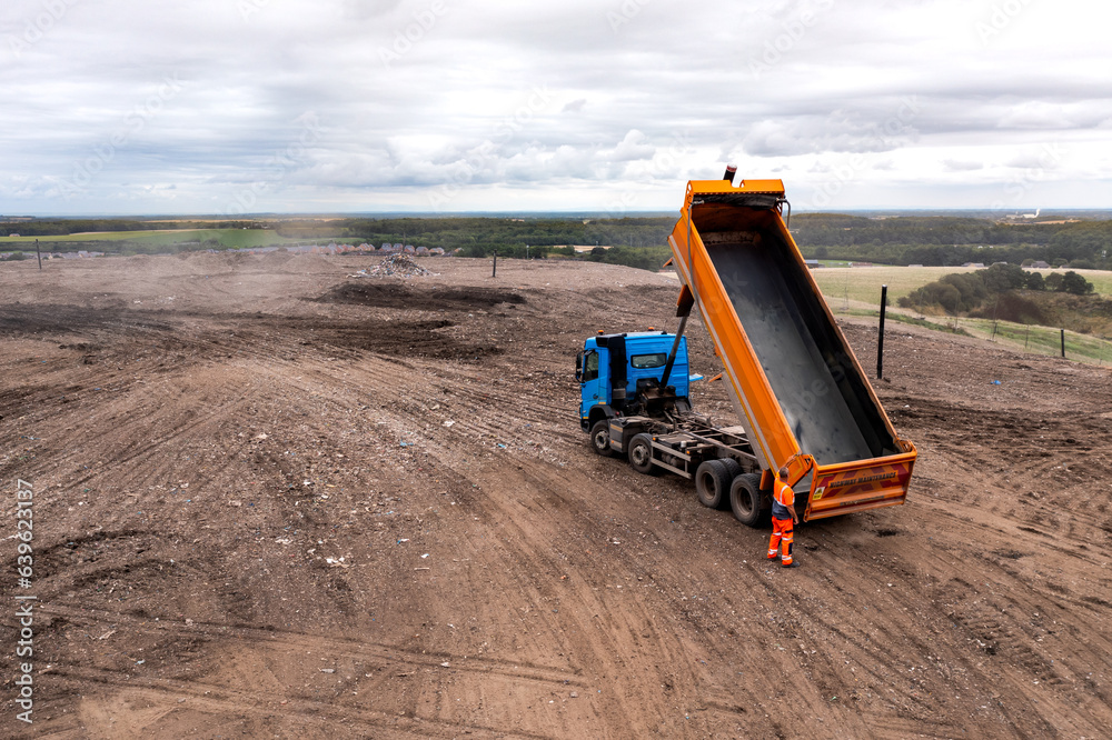 Aerial view of a tipper truck with raised trailer on a landfill site ...